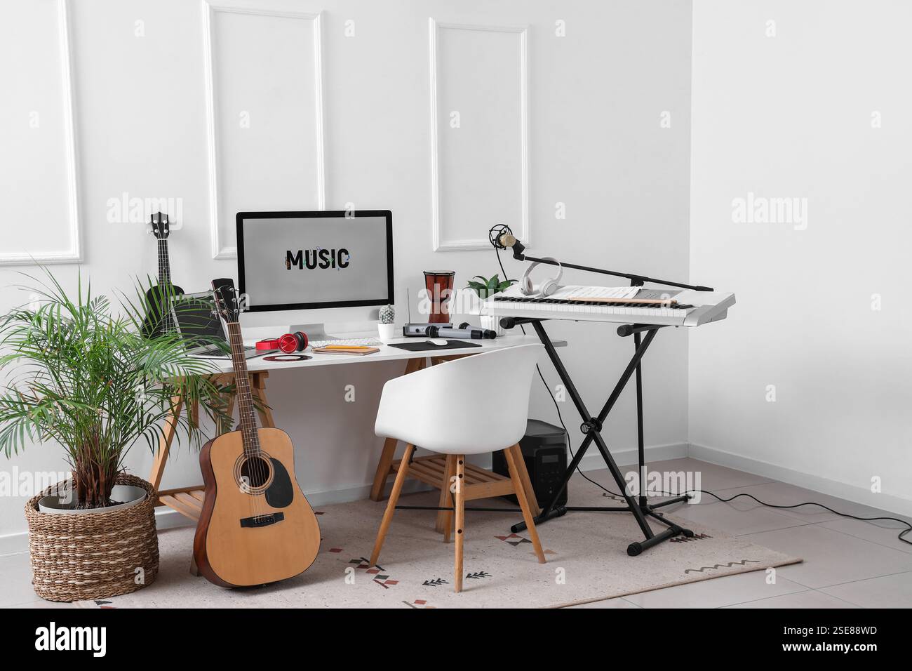 Workplace with computer and musical instruments near light wall in ...