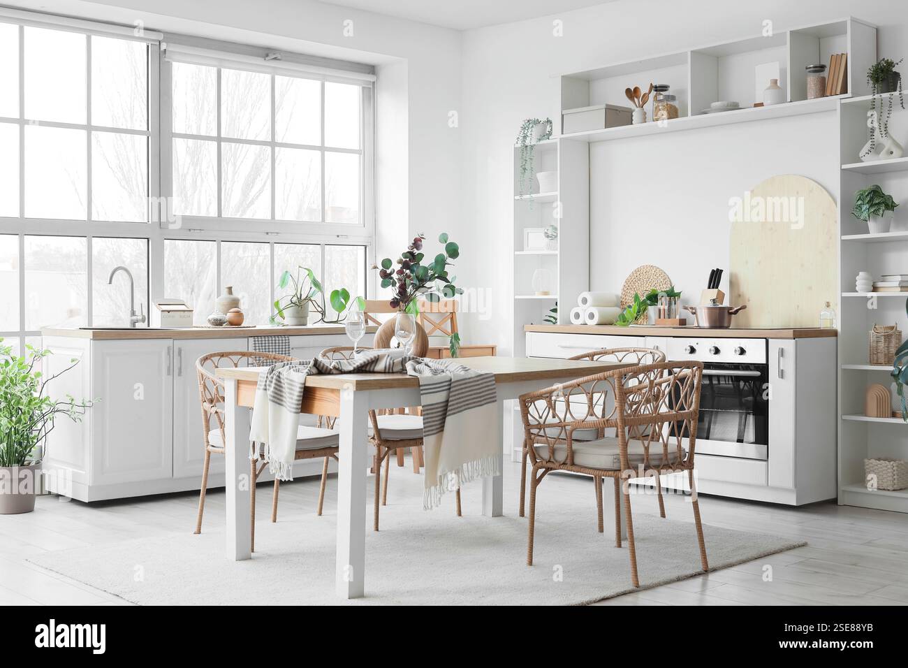 Interior of light kitchen with dining table, counters and shelf unit ...
