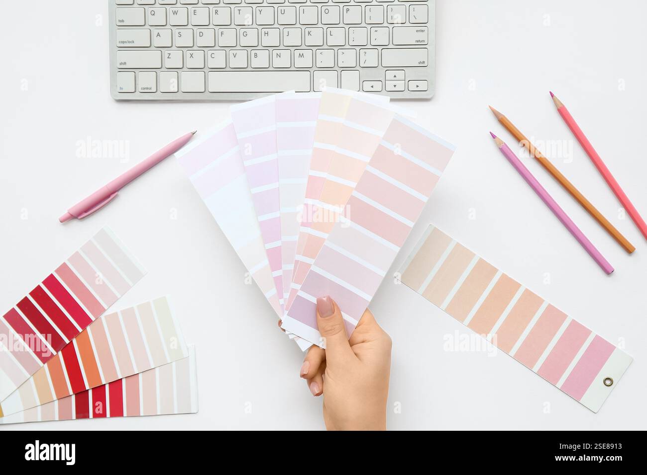 Female hand with paint color palettes, pencils and computer keyboard on ...