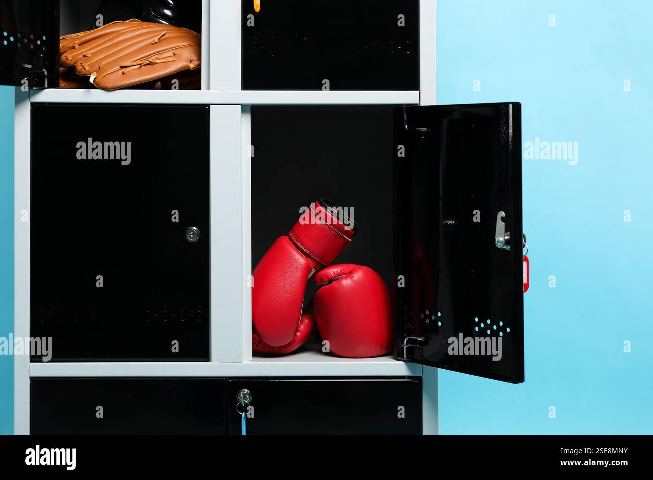 Open lockers with sport equipment on light blue background Stock Photo ...