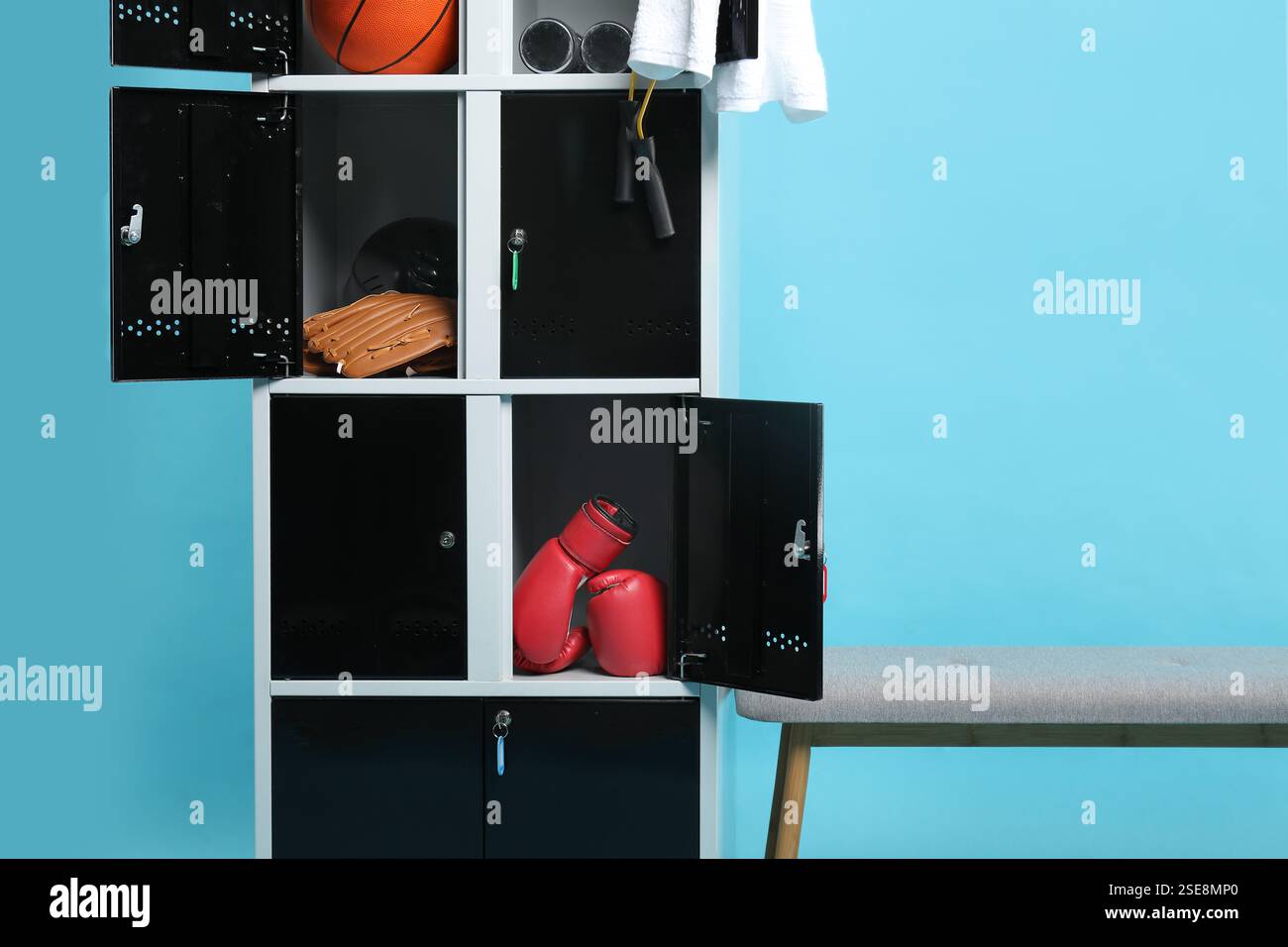 Open lockers with sport equipment and bench on light blue background ...