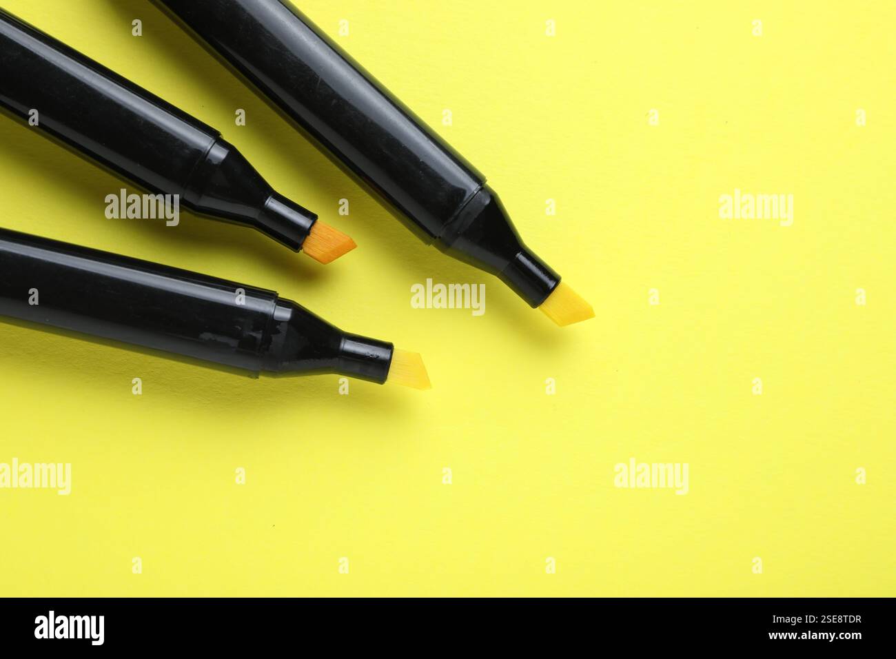 Color double sided markers on yellow background, top view. Space for ...