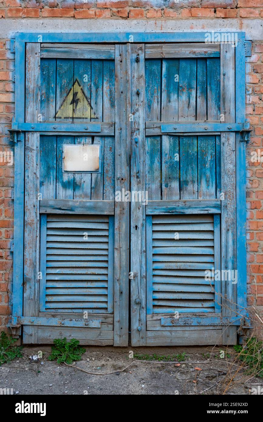 Distressed blue doors with wooden slats stand in an industrial setting ...