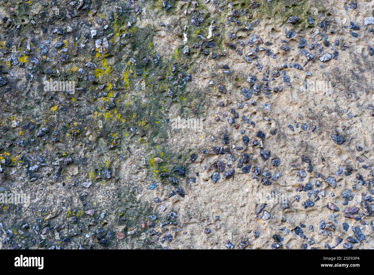 Close-up view of a weathered wall featuring various stones, patches of ...