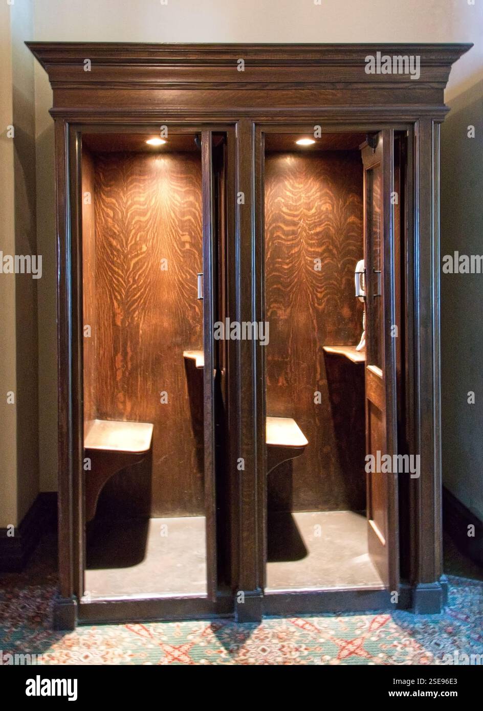 A vintage wooden telephone booth with rich, dark wood paneling, glass ...