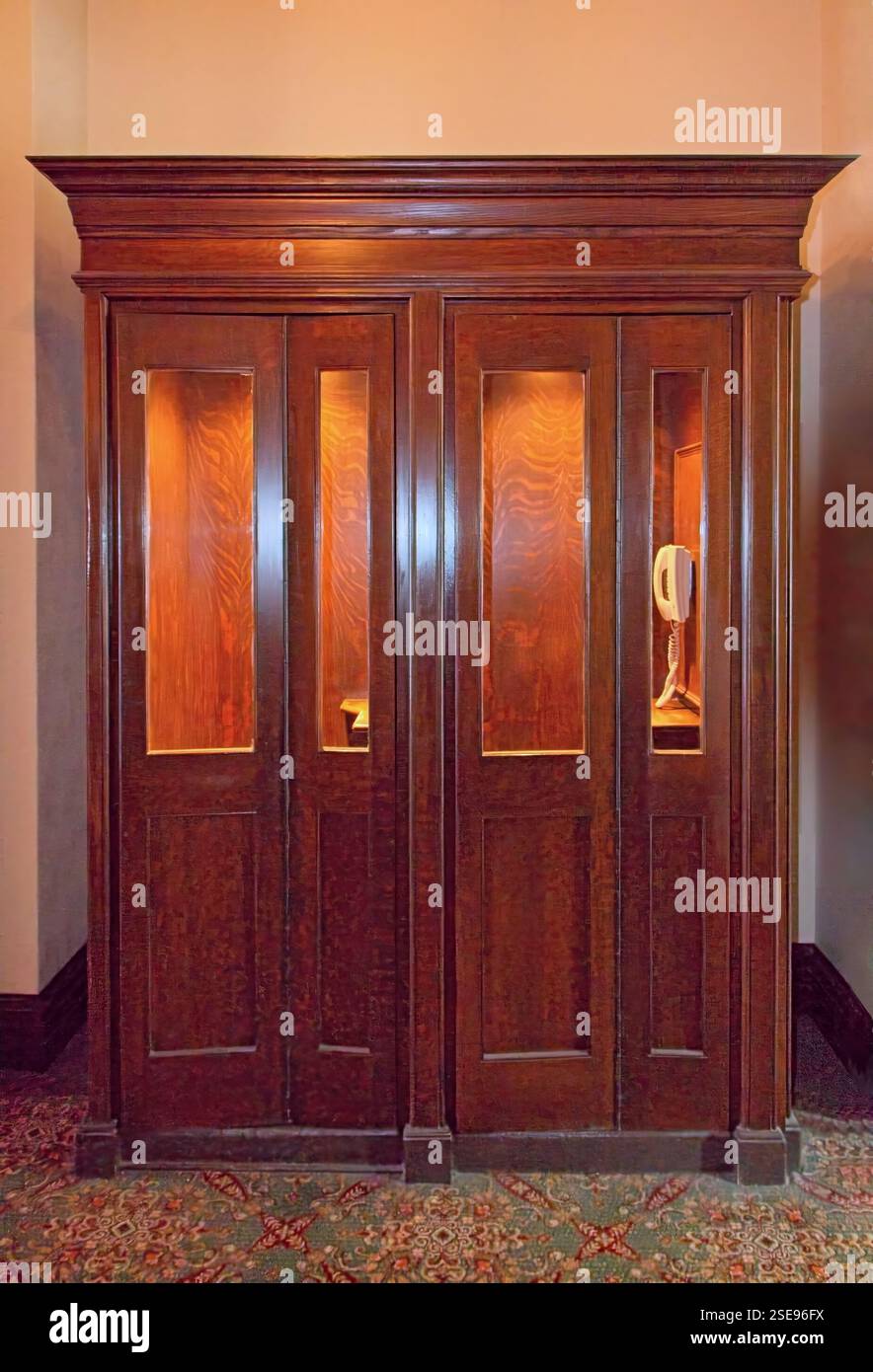 A vintage wooden telephone booth with rich, dark wood paneling, glass ...
