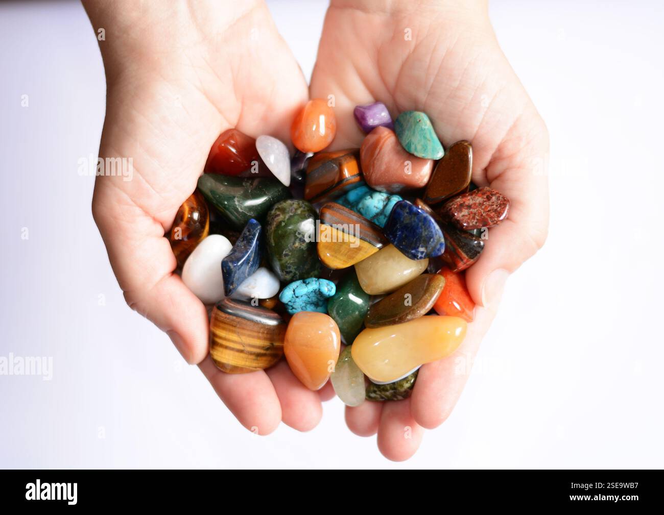 A young woman holding a collection of various raw and shiny mineral ...