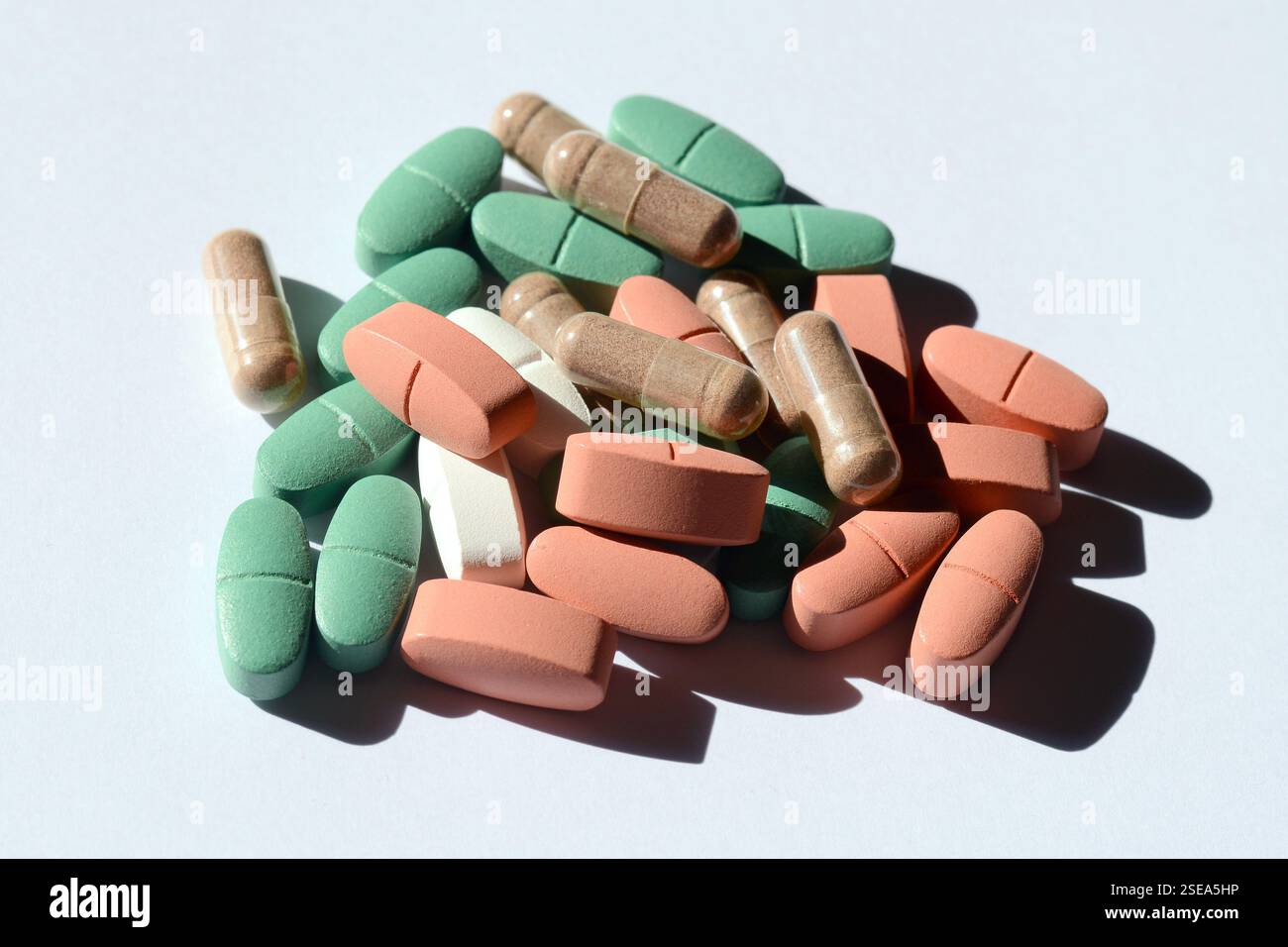 Various colorful pills and capsules scattered on white background ...