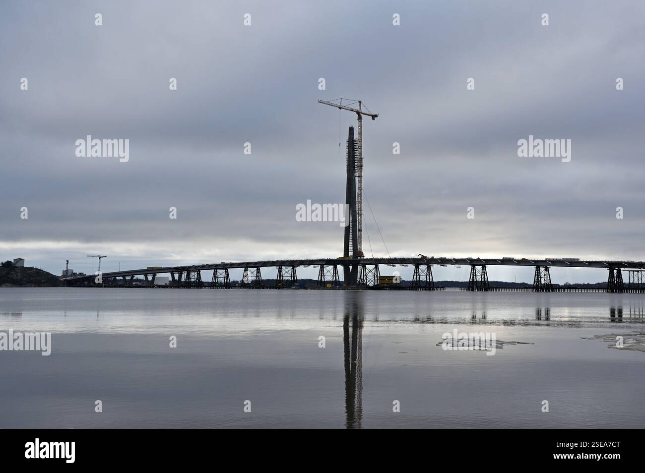 A large-scale bridge construction project stretches across a calm body ...