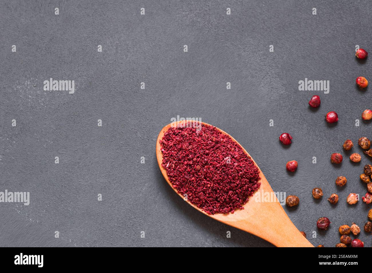 Dried ground red Sumac powder spices in wooden spoon on rustic table ...