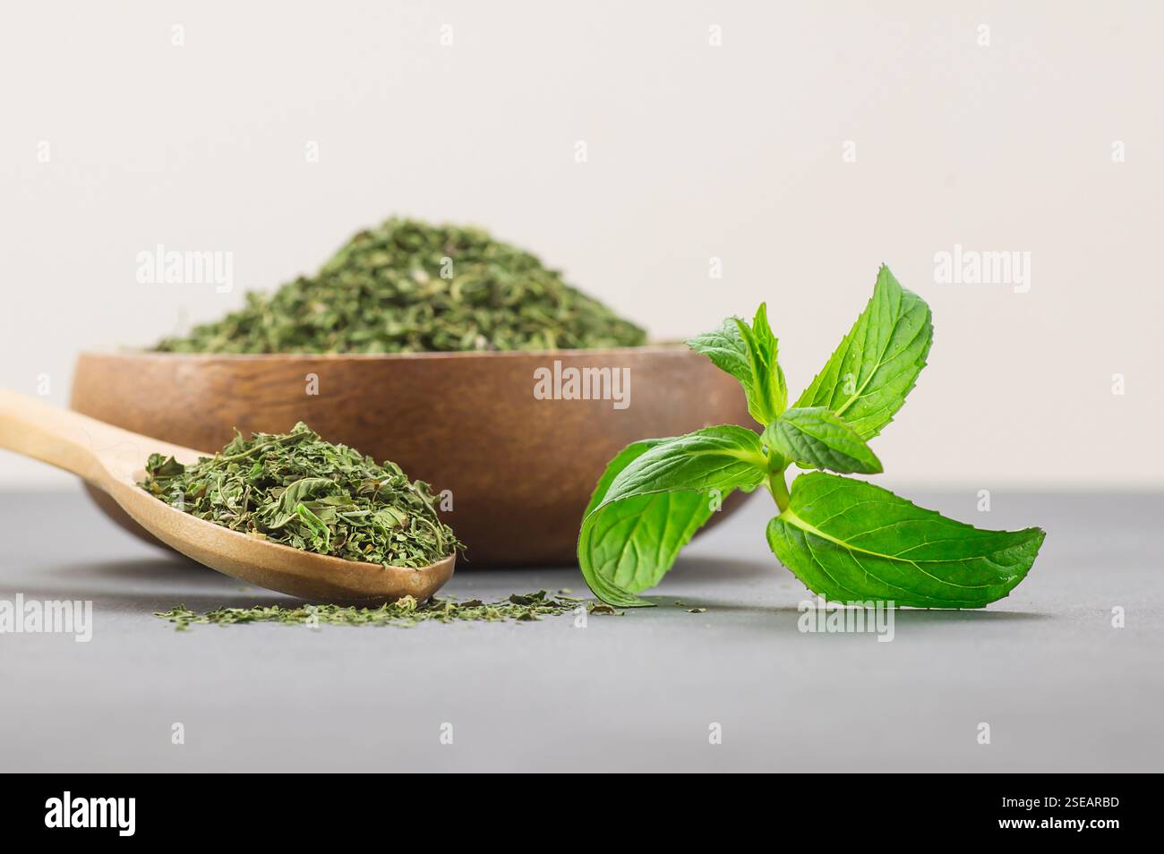Fresh green peppermint leaves and dried mint leaves in wooden spoon on ...