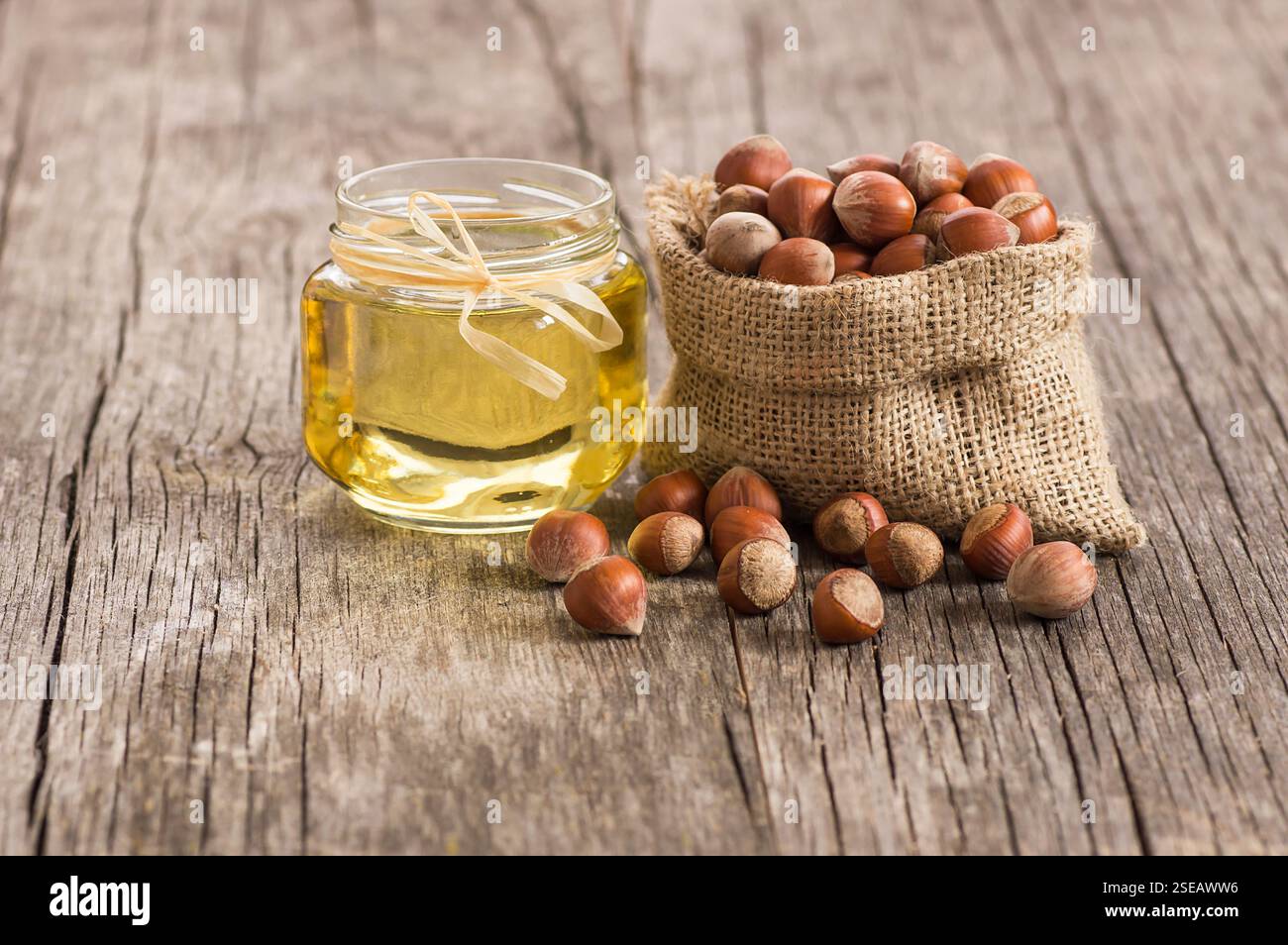 Hazelnuts, filbert in burlap sack and hazelnut oil in glass of bottle ...
