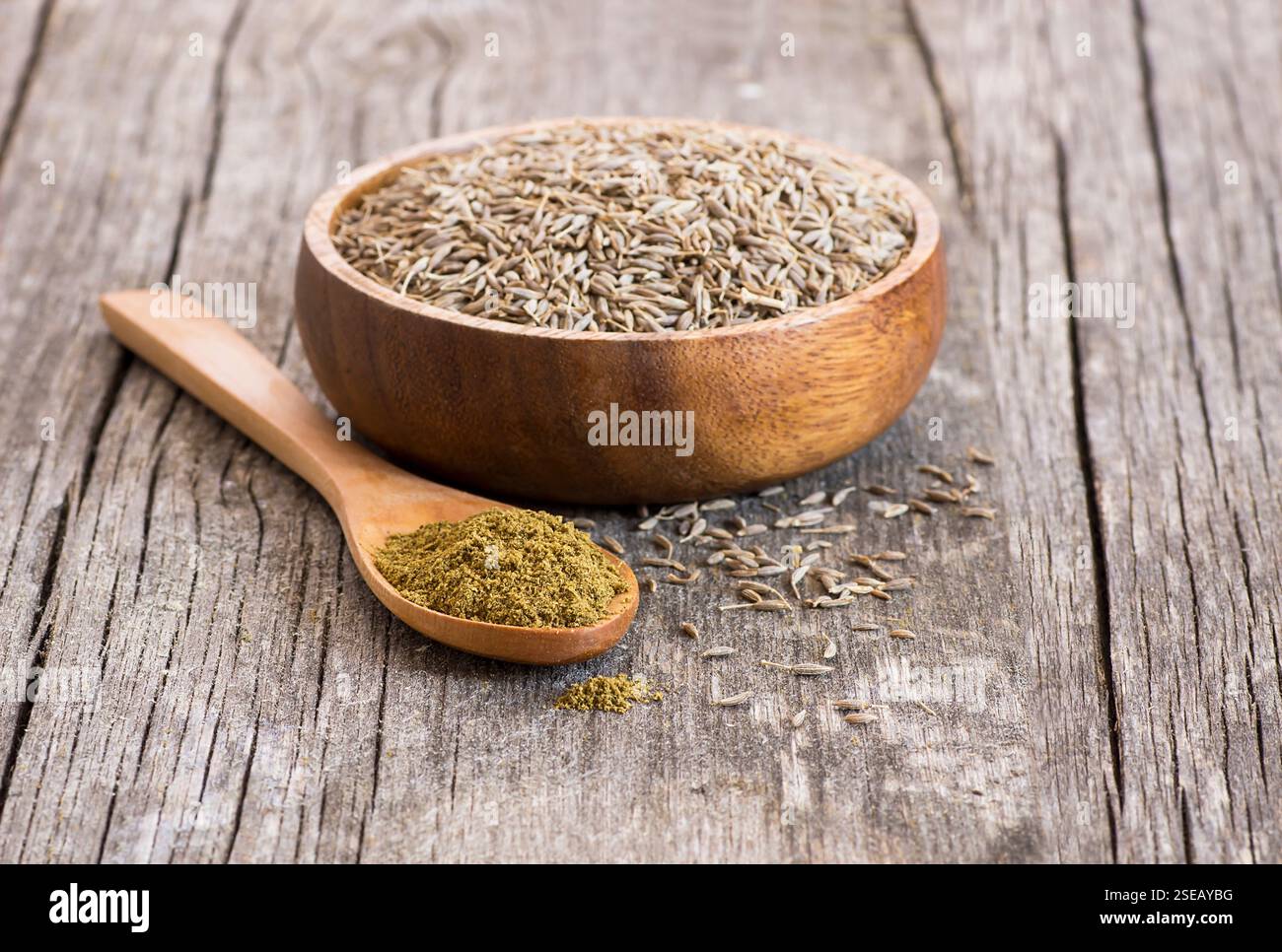 Pile of dry caraway spice with ground caraway powder in wooden spoon ...