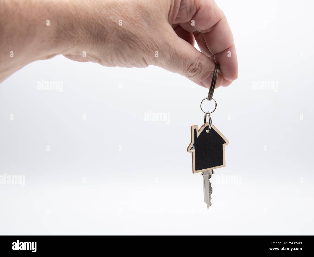 Mano sujetando un llavero de madera con forma de casa con una llave, aislado en blanco Stock ...