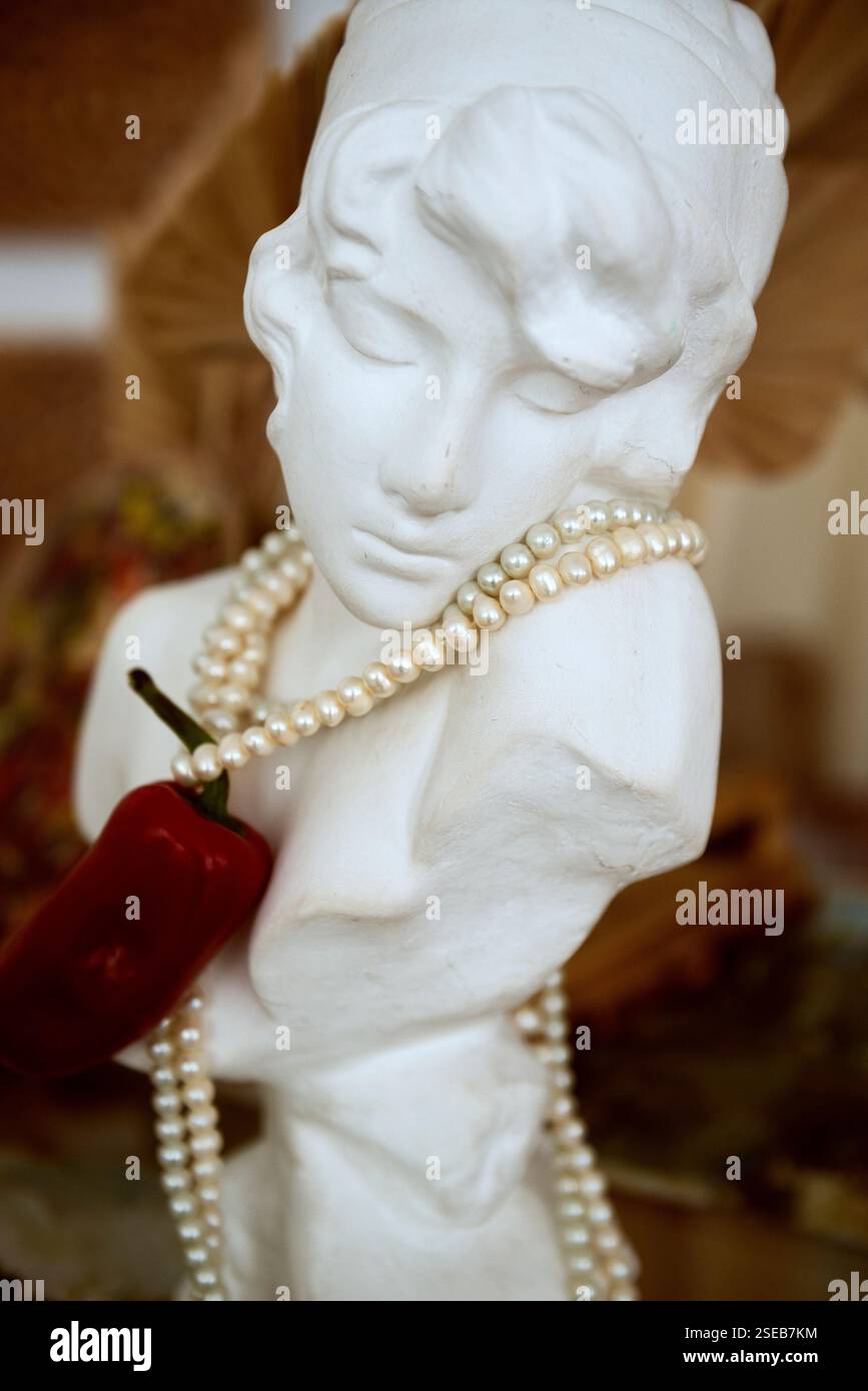 bust of a plaster girl with pearls and red hot peppers on her neck ...