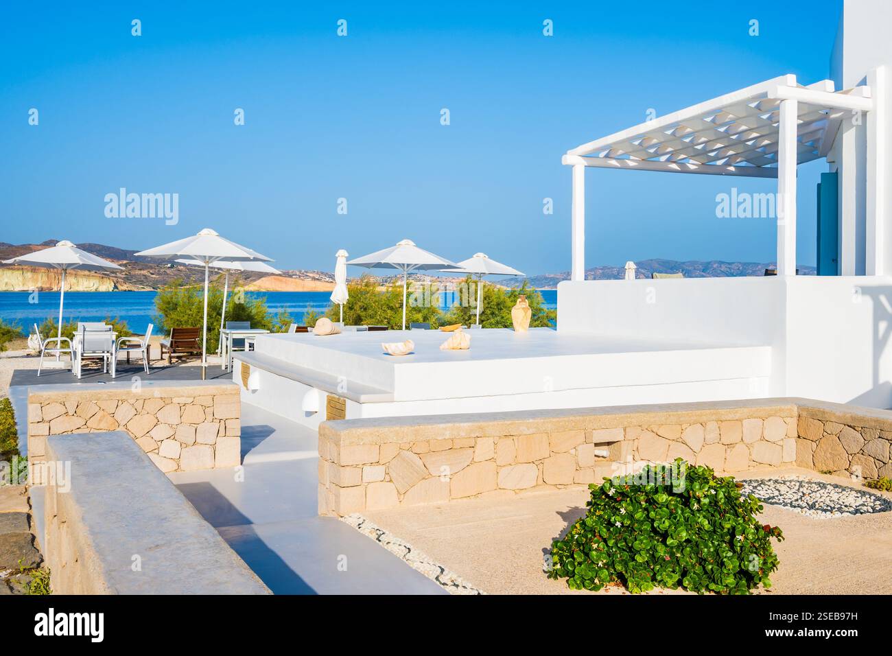 Walkway to beach with umbrellas and traditional Greek architecture in ...