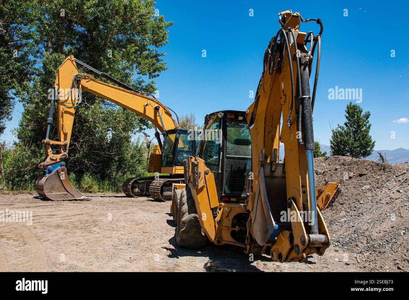 Heavy duty construction equipment on a job site. A yellow backhoe and ...