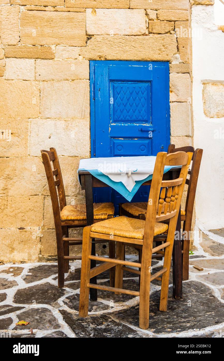 Three wooden chairs and table of a Greek restaurant tavern in narrow ...