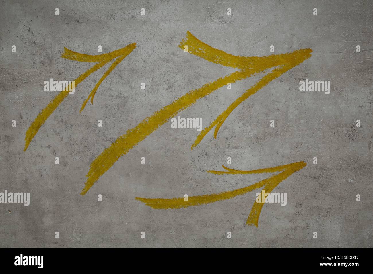 Three golden painted arrows on grey background Stock Photo - Alamy