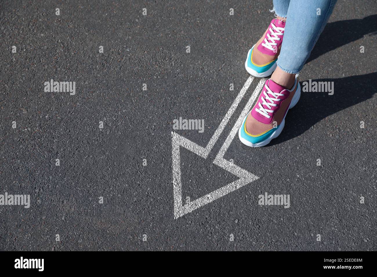 Woman walking on asphalt road with white arrow, closeup. Concepts of ...