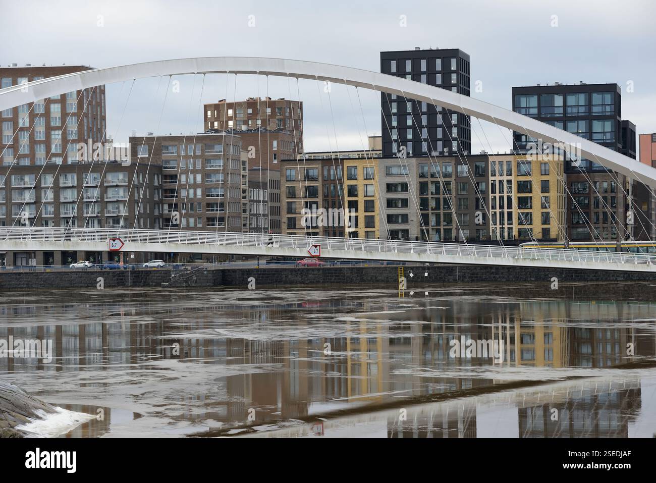 A modern white arch pedestrian bridge in Helsinki, Finland, spans over ...