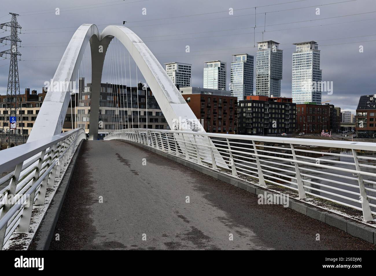 A modern white arch pedestrian bridge in Helsinki, Finland, spans over ...