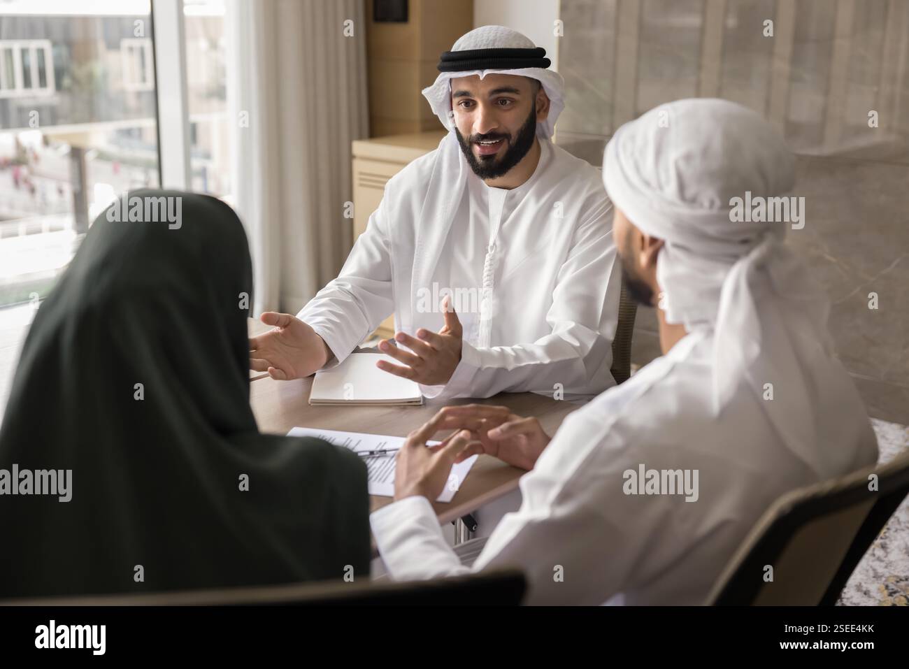 Arabian professionals dressed in traditional Muslim robe discussing ...