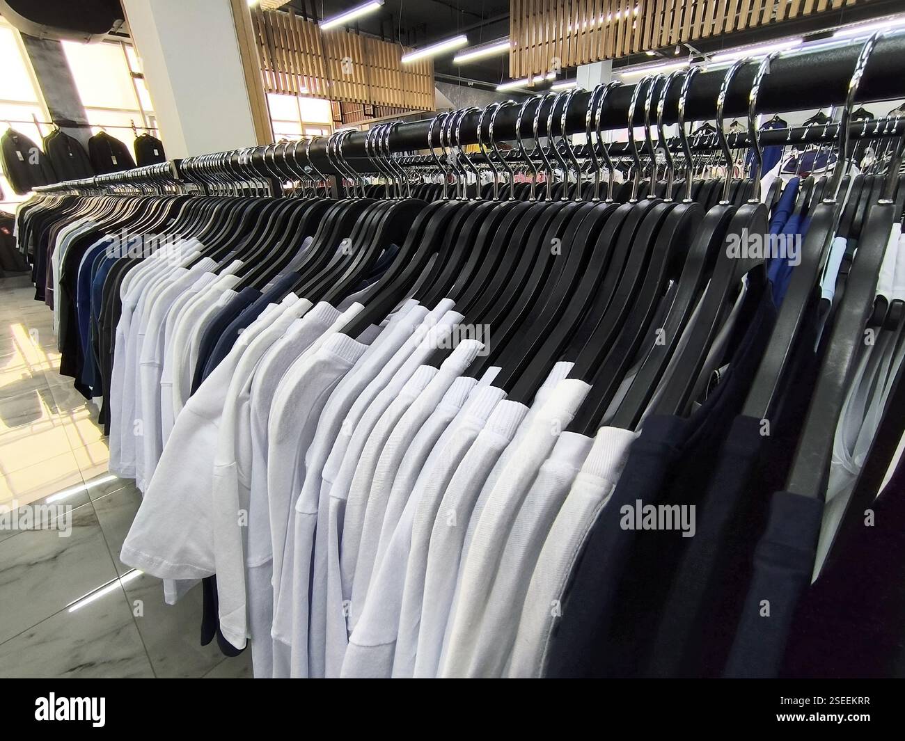 Clothing store rack with various styles of shirts in a modern retail ...