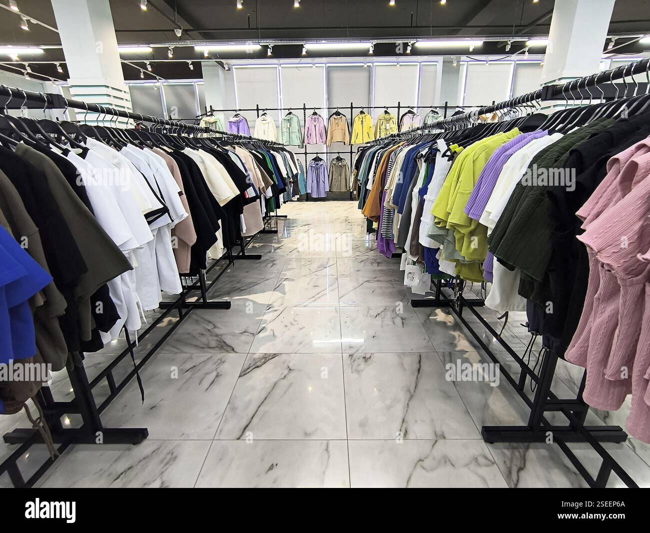 Modern clothing store interior with colorful garments on display racks ...