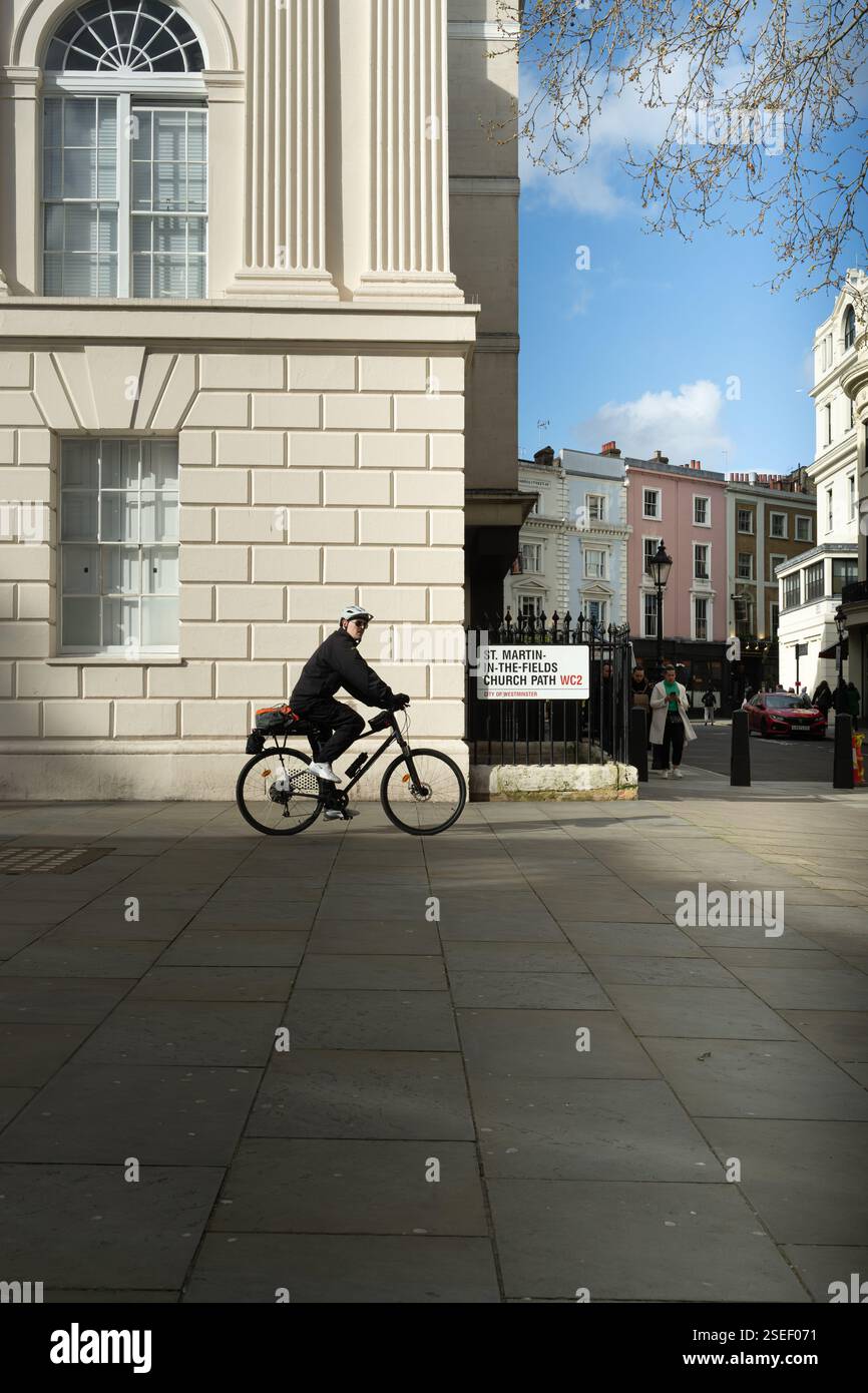 Cyclist on St. Martin-in-the-Fields Church Path, London WC2. A man ...