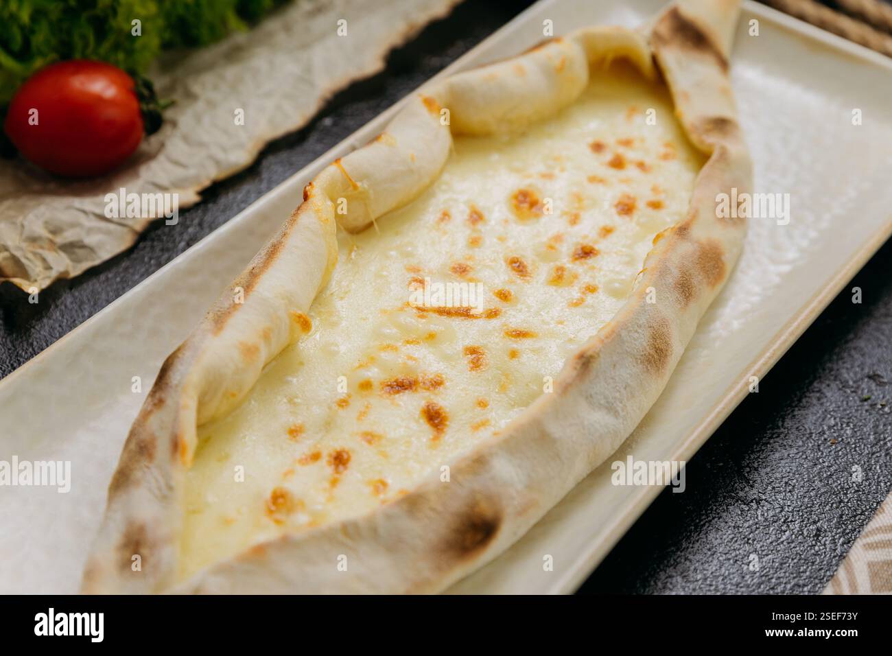 Turkish cheese pide with melted mozzarella on a plate in elegant and ...