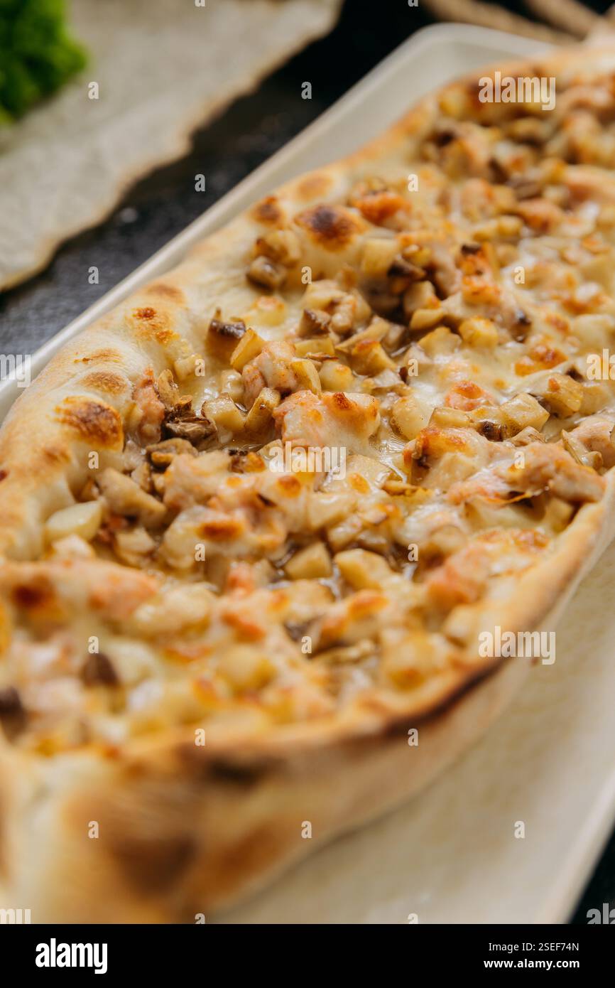 Turkish pide with diced chicken, cheese, and vegetables on plate in ...