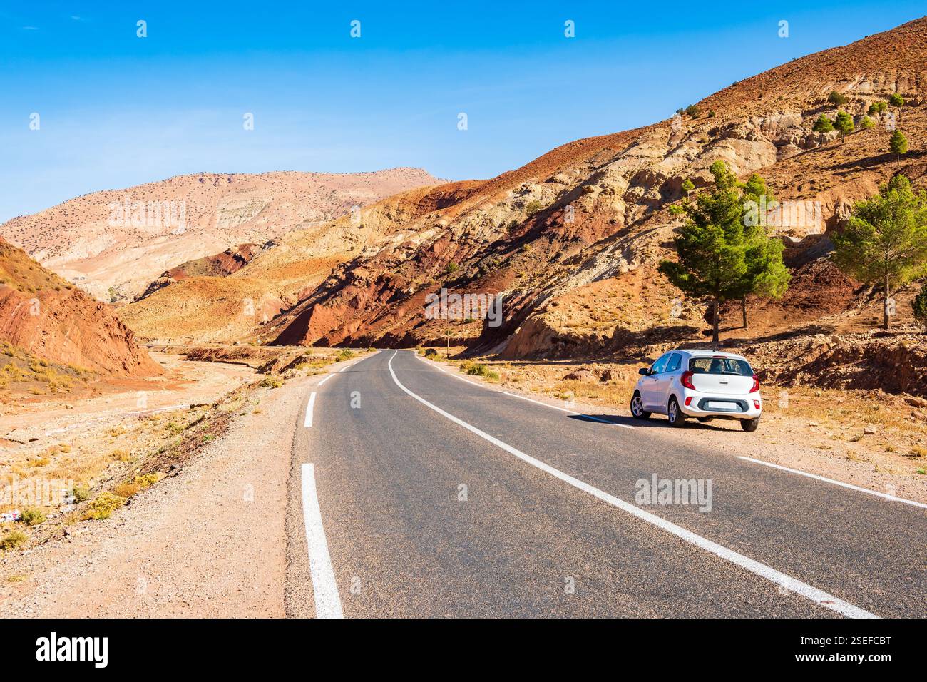 Rental car parking near paved asphalt road in Atlas mountains with high ...