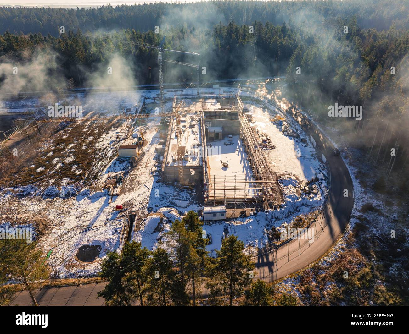Snow-covered construction site with scaffolding, surrounded by dense ...