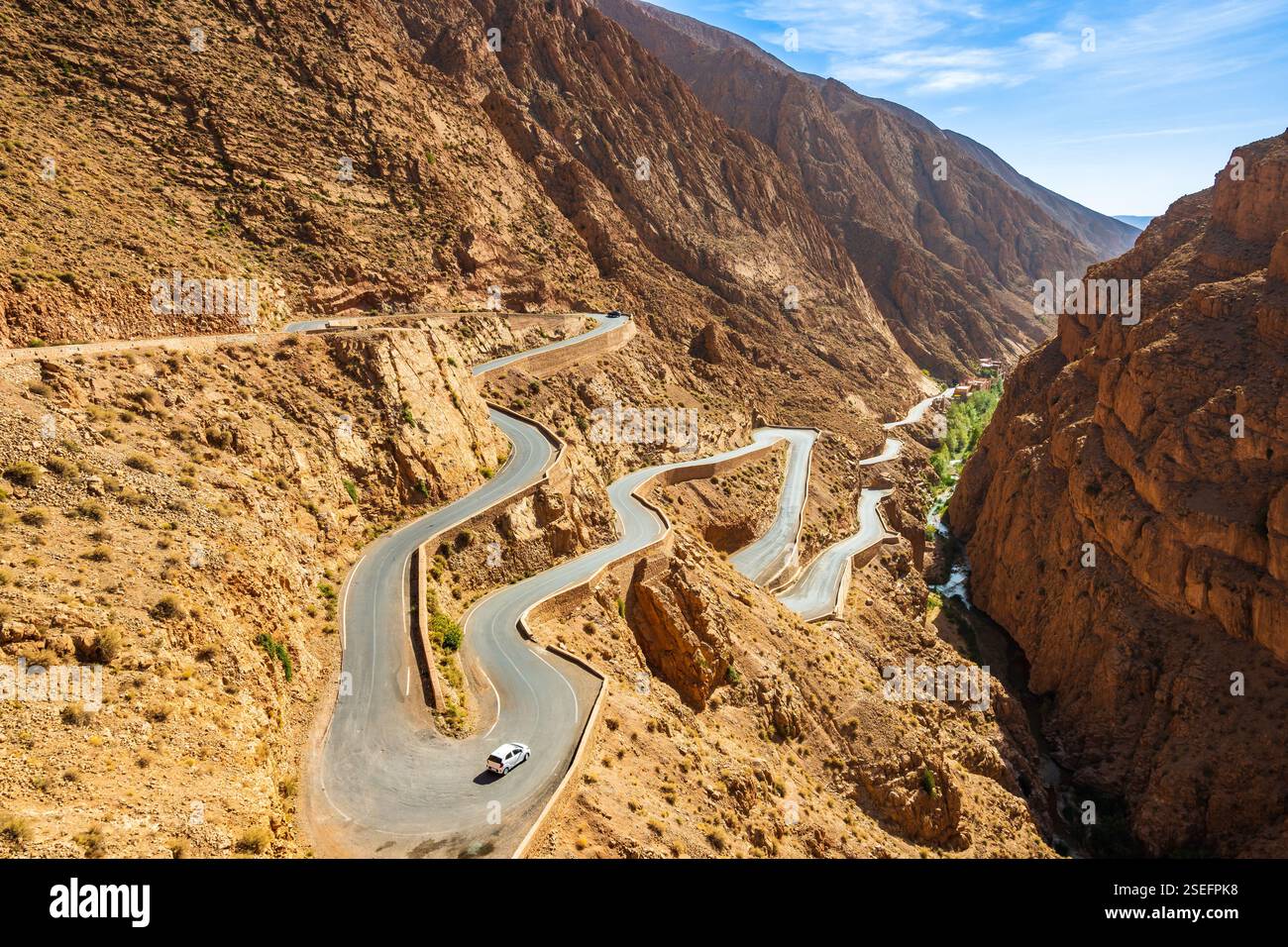 Car driving on zig zag road bends in desert mountain landscape of Dades ...