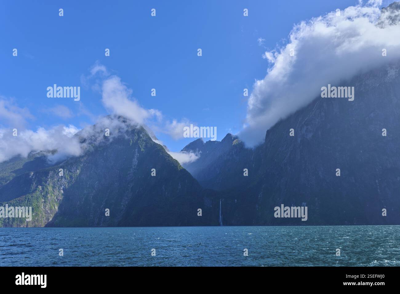Twisted clouds envelop majestic mountains over the sea, fjord landscape ...