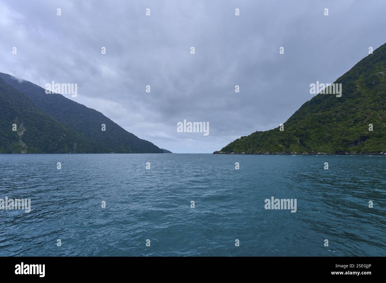 Wide water under grey sky with distant mountain ranges, fjord landscape ...