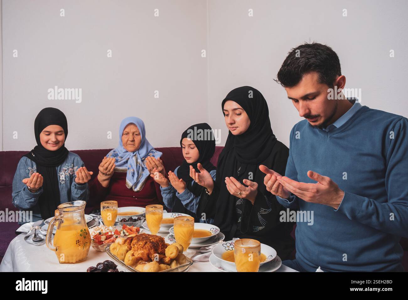 Muslim family making iftar dua to break fasting during Ramadan happy ...