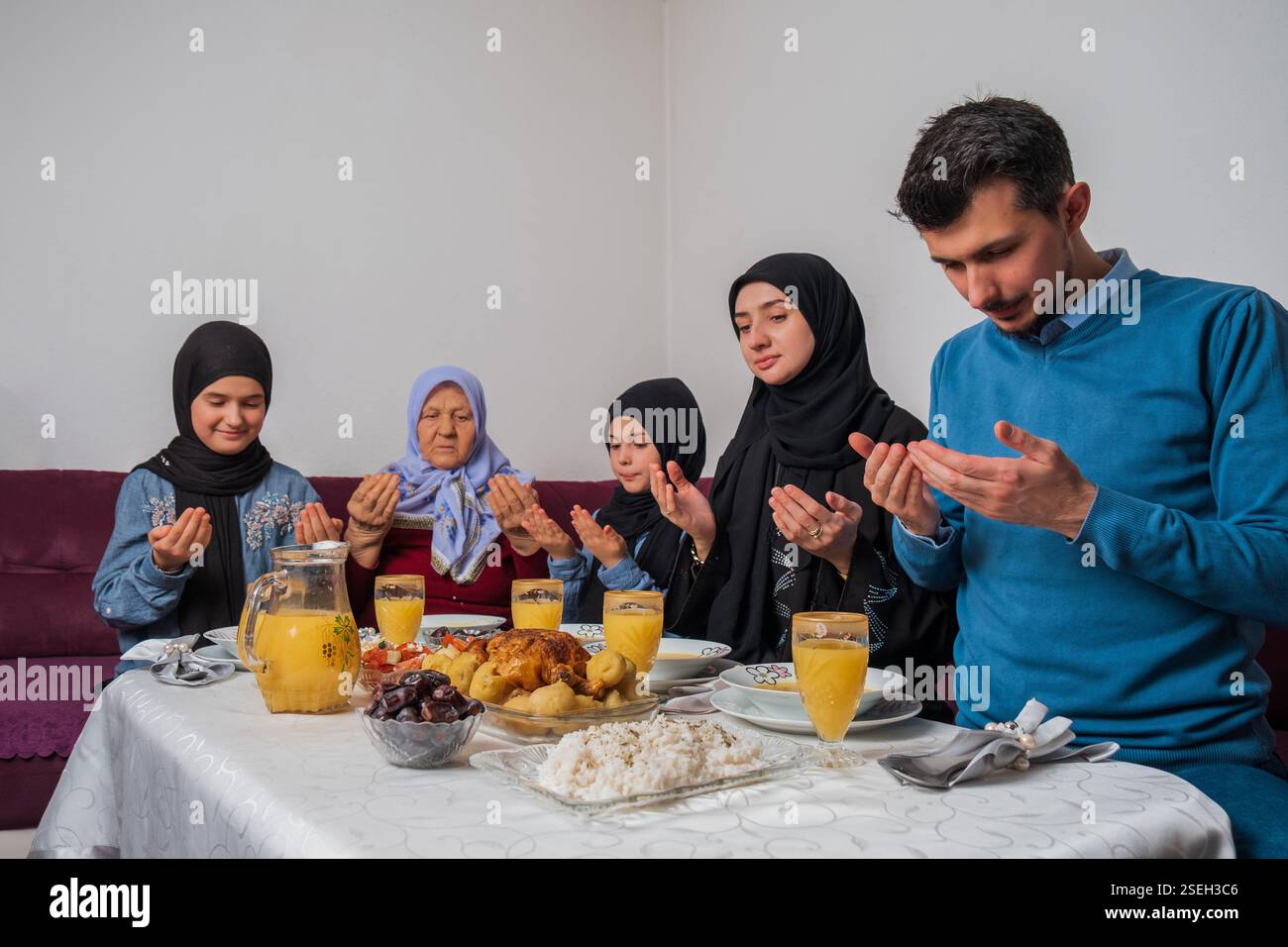 Muslim family making iftar dua to break fasting during Ramadan happy ...