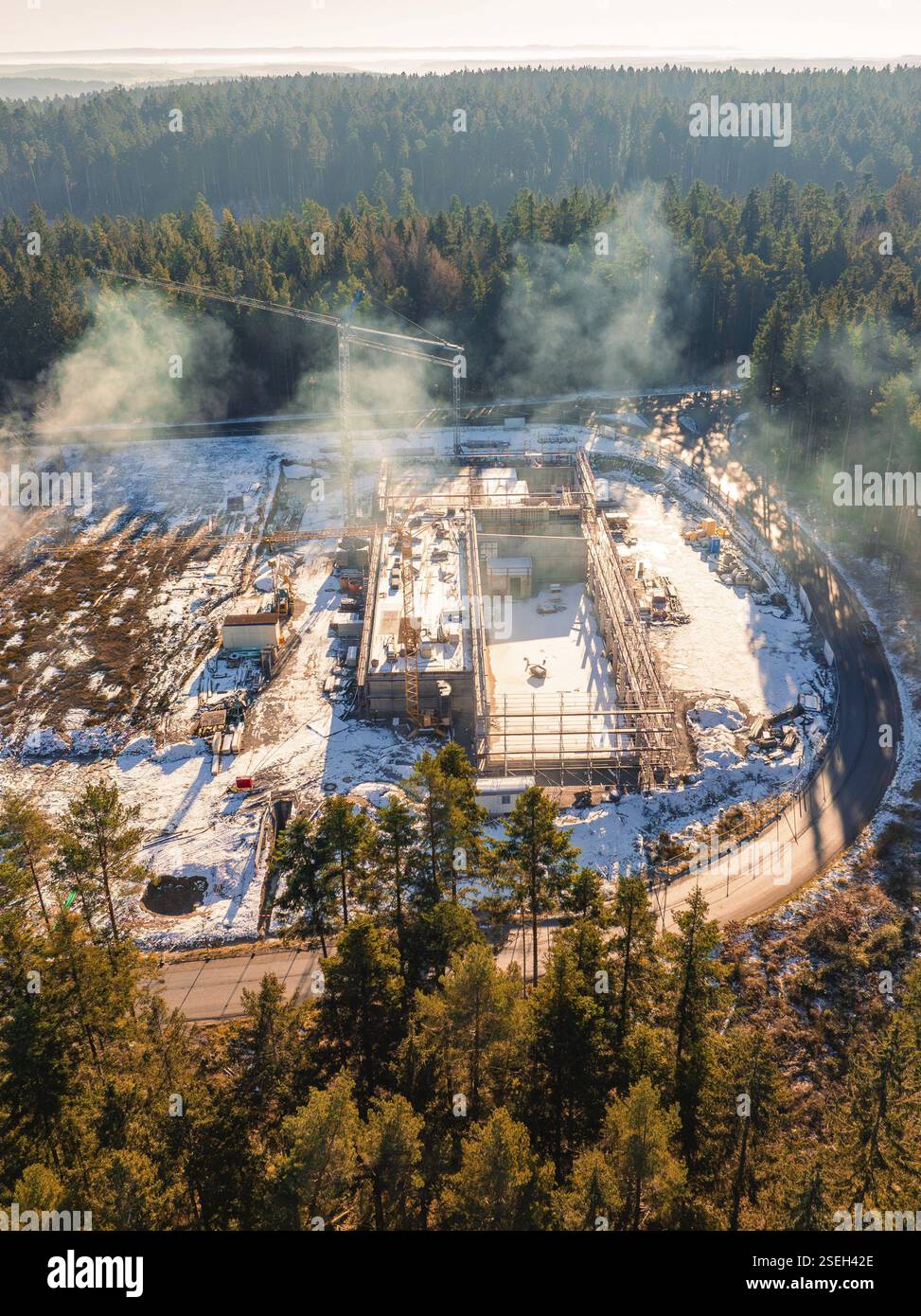 Snow-covered construction site in the forest with cranes and areas ...