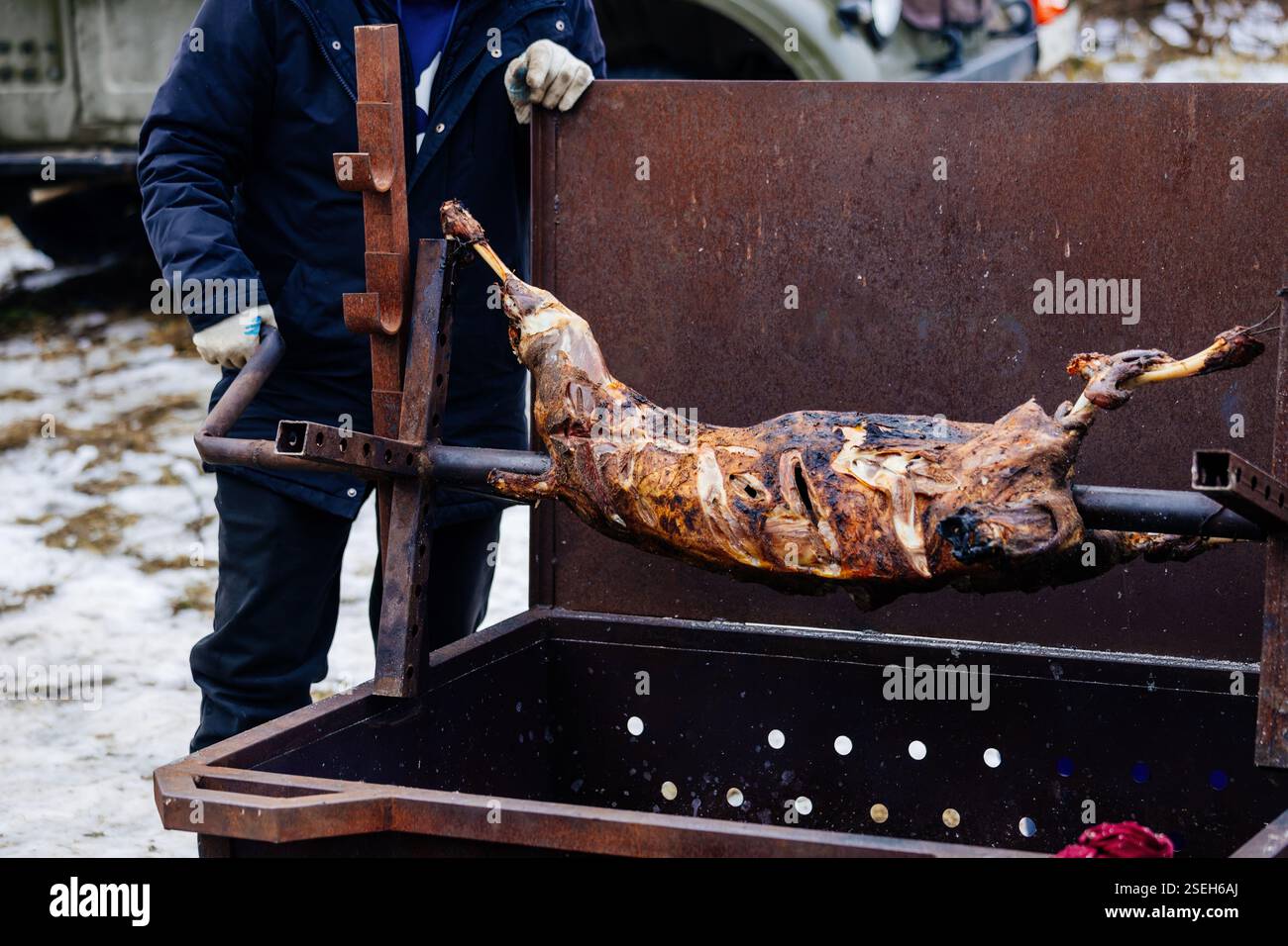Man frying lamb on barbecue spit Stock Photo - Alamy