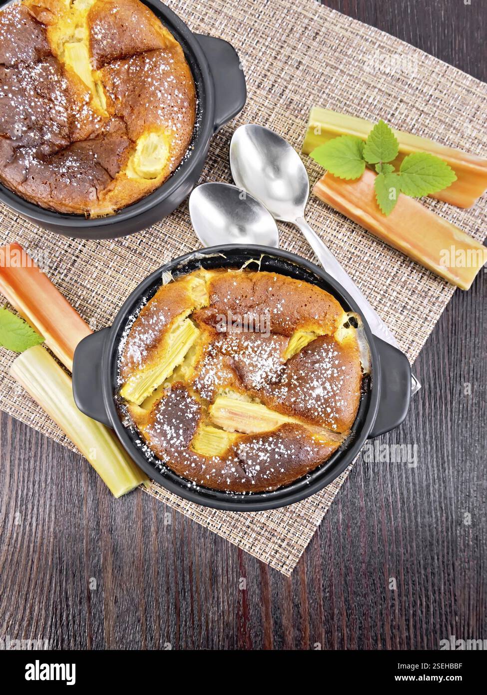 Pie clafouti with rhubarb in brazier, mint and rhubarb stems on napkin ...