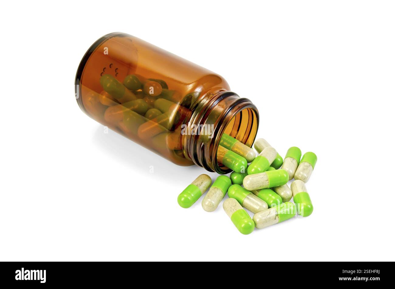 Green capsules in an open brown glass and on the table against a white ...