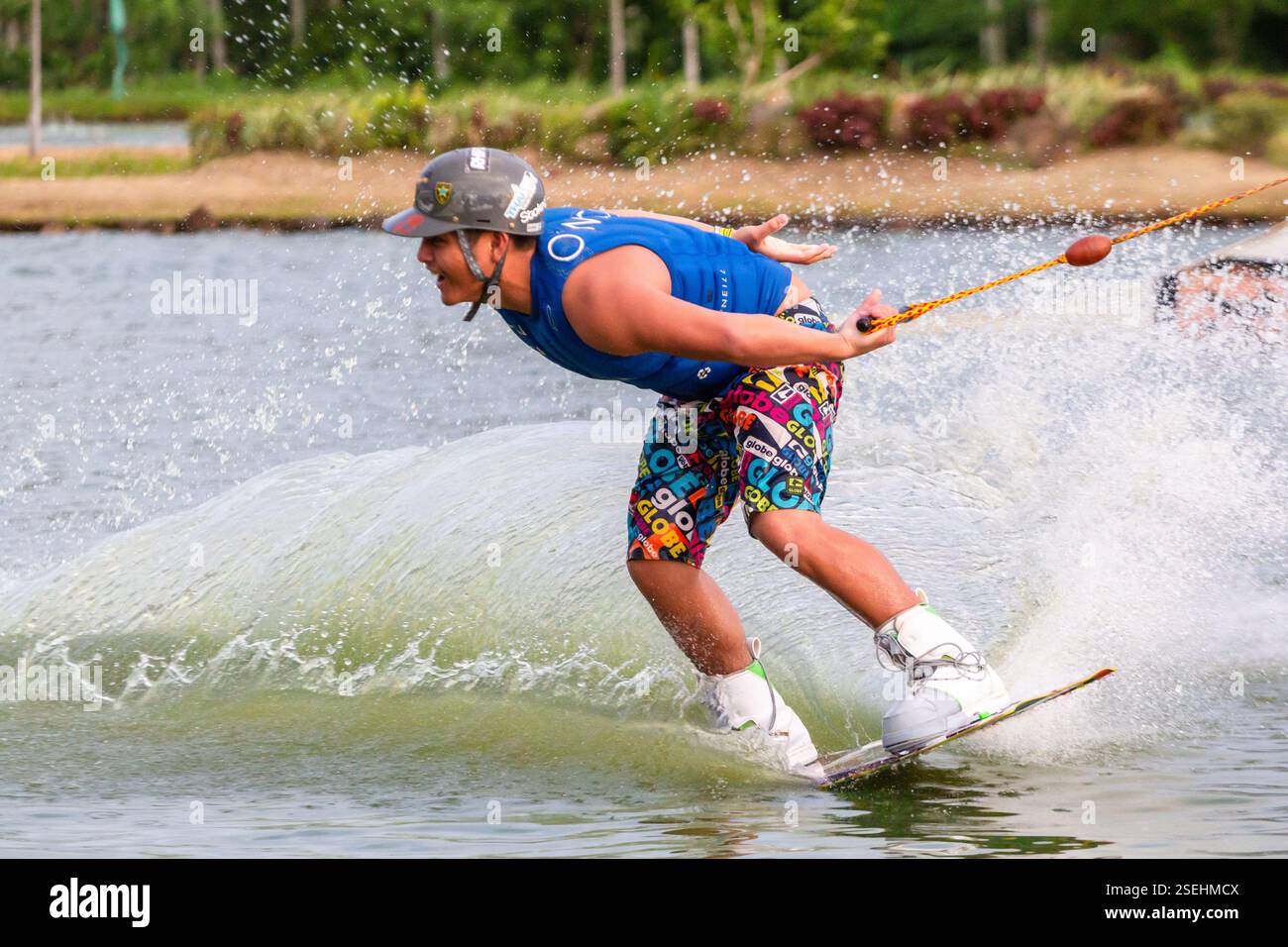 A young adult male wakeboarding at full speed in a wakeboard park in ...