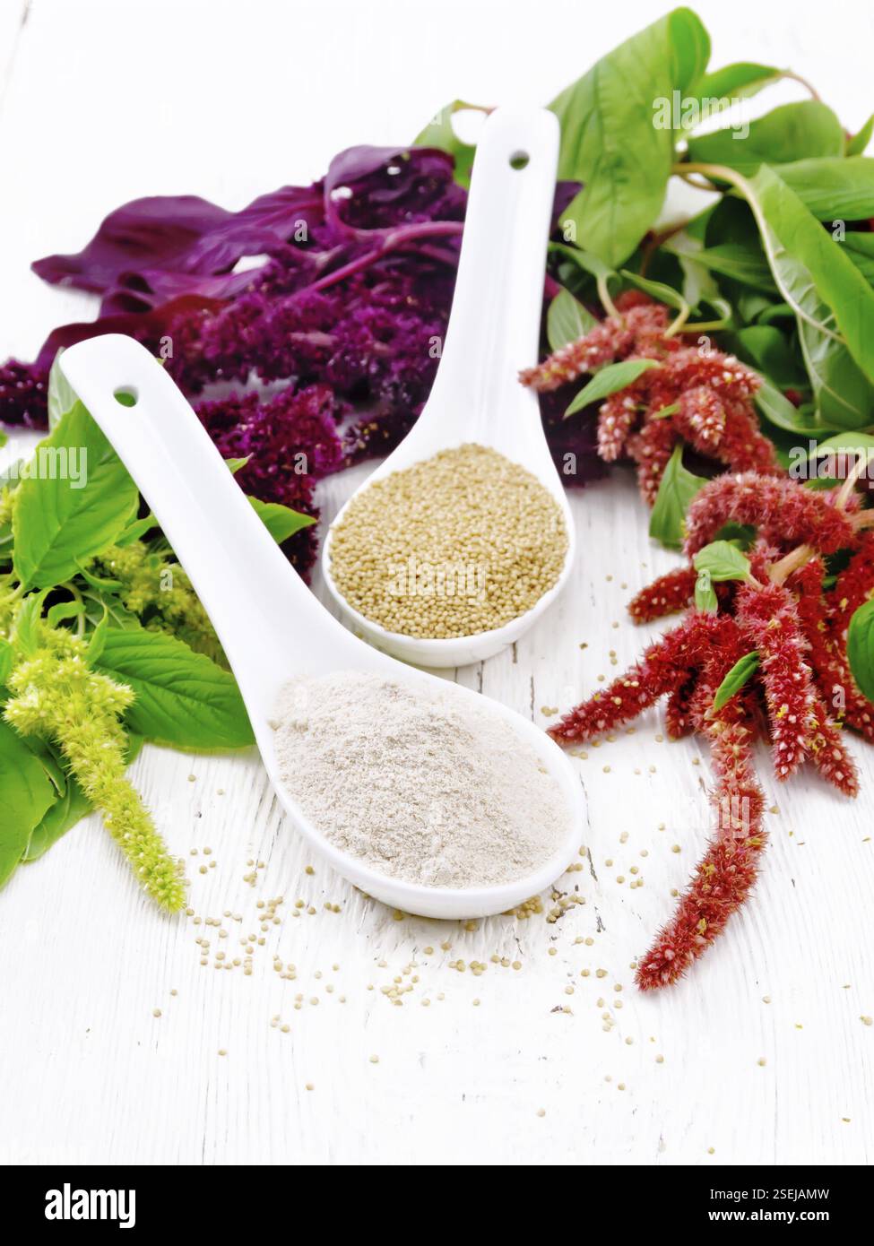 Flour and seeds amaranth in two spoons, multicolored flowers and leaves ...