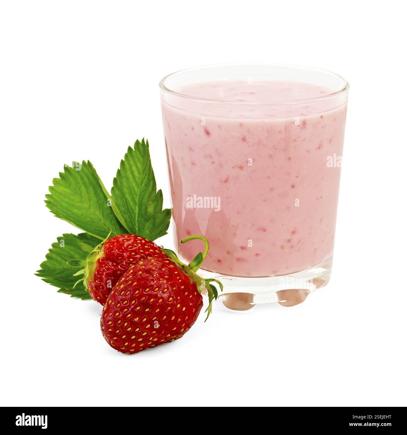 Glass with the milkshake, two berries and a green strawberry leaf are ...