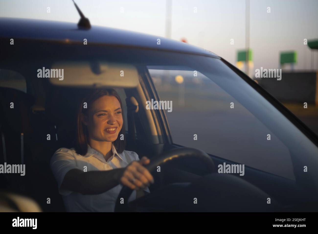 Focus on a woman driving at night, highlighted by headlights and an ...