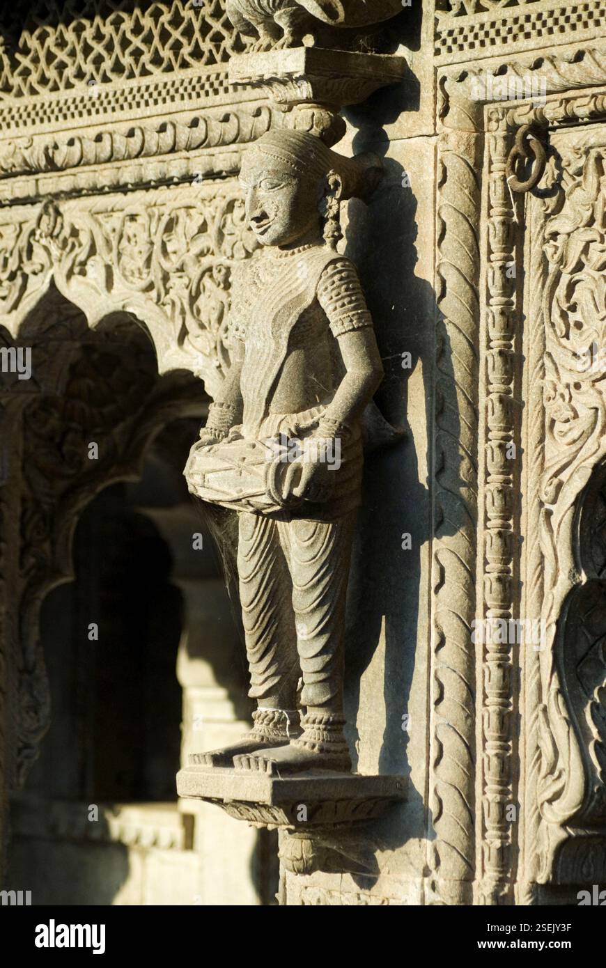 Woman dancer playing drum music instrument carved in stone on wall of ...