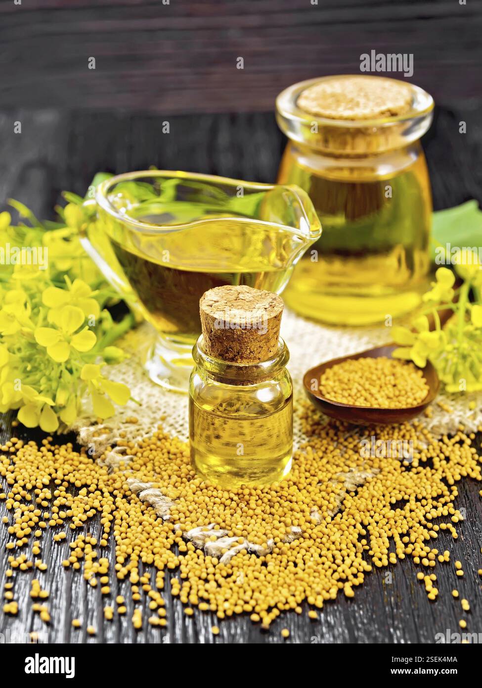 Mustard oil in two glass jars and a gravy boat, grains, leaves and ...