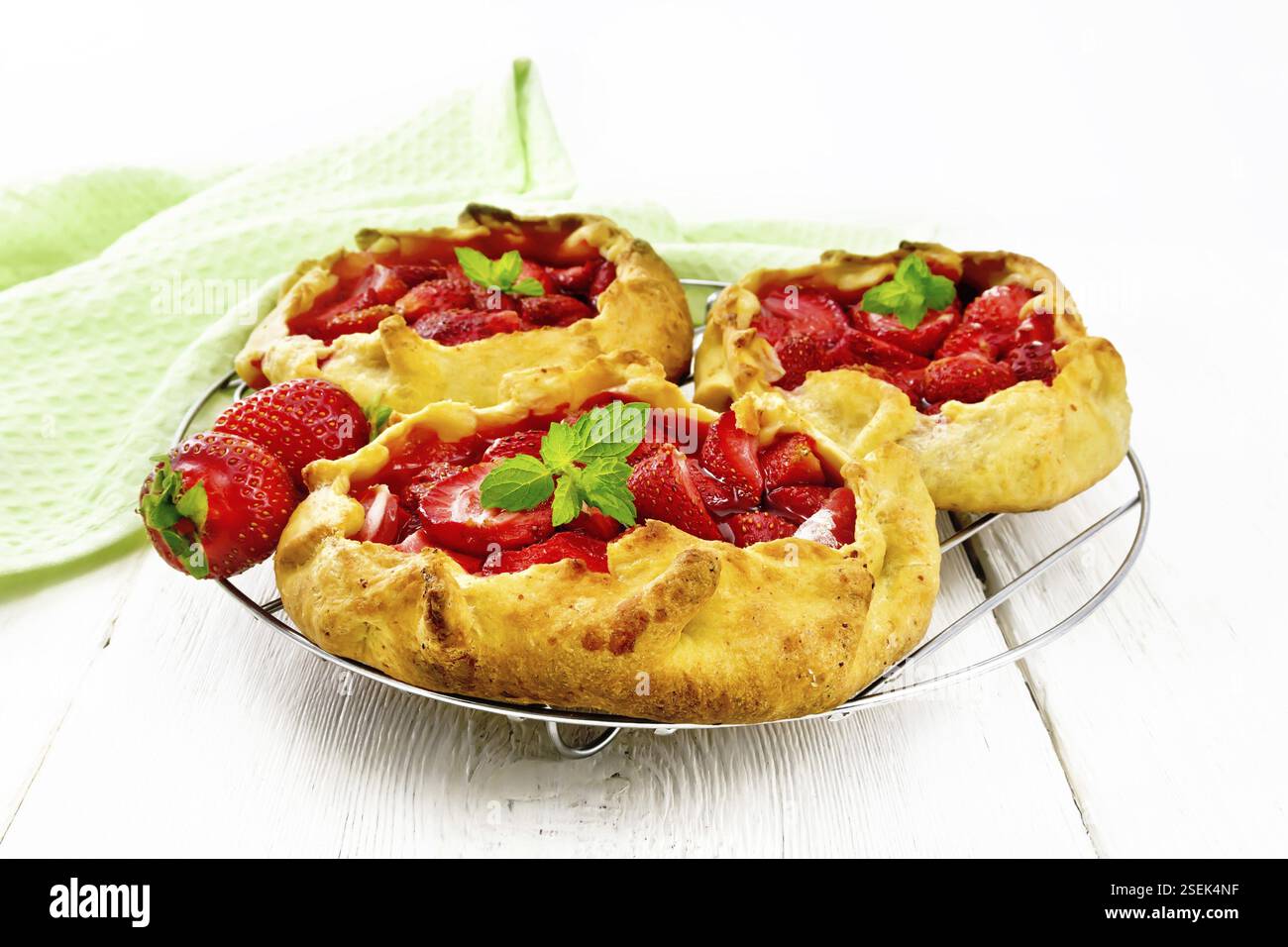 Small pie with strawberries on a metal grille, a towel on the ...